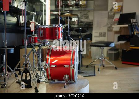 A bright red drum set that features a shiny cymbal placed on top of it ...