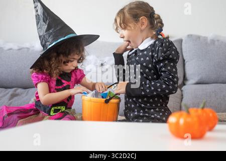 kids in halloween costumes sharing candies at home Stock Photo - Alamy