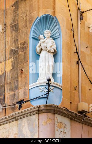 White Stone Religious Statue Integrated into Rustic Building Corner ...