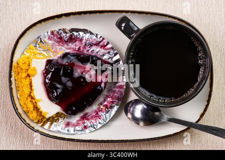 a dark ceramic cup with expresso on a plaster tray with coffee beans ...