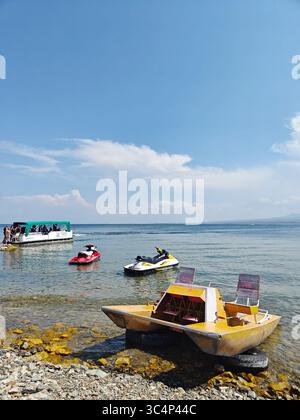 Sevan Lake, Armenia - July 19, 2025: Vibrant jet skis and boats are anchored at a beautiful ...