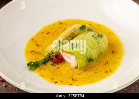Zucchini-wrapped fish fillet in saffron-infused yellow sauce Stock ...