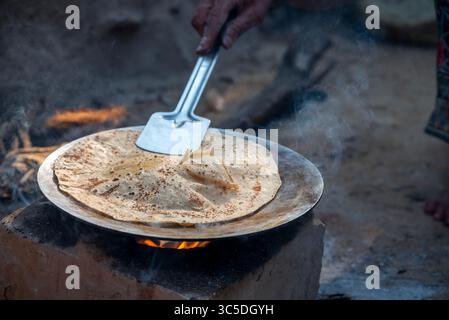 A village woman makes bread on the stove. cooking bread in clay stove ...
