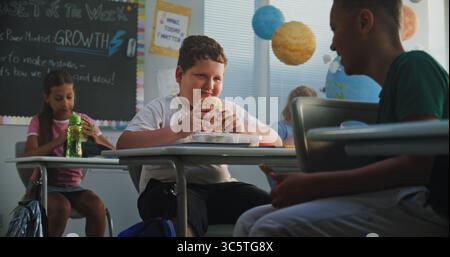 Happy diverse schoolchildren sitting at desks in school classroom Stock ...