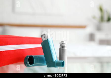 Modern inhaler, asthma aerosol canister and first aid kit on glass ...