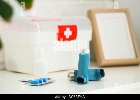 Modern inhalers, pills and first aid kit on chest of drawers, closeup ...
