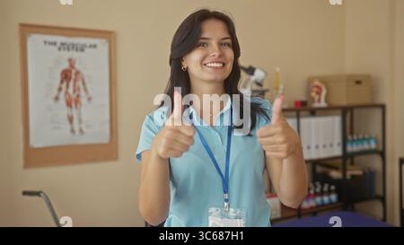 Young hispanic woman wearing physiotherapist uniform standing at clinic ...
