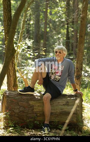 man sits on tree trunk in forest using laptop computer Stock Photo - Alamy