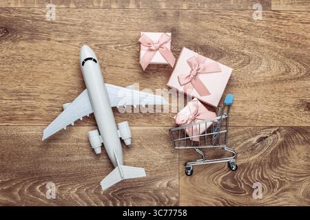 Air delivery. Plane figurine, shopping trolley and gift boxes on blue ...