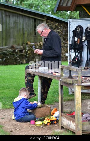 A small boy with father and grandfather sitting in apple orchard in ...
