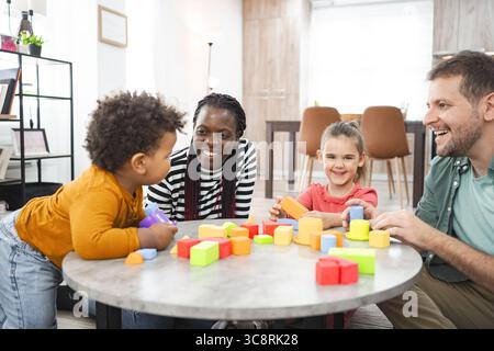 Multiracial family playing with colorful blocks in bright living room ...