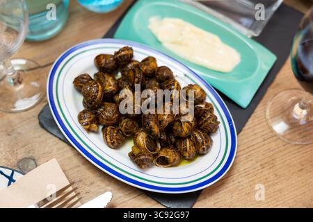 Plate of Caracoles cooked in shells on grill aioli sauce Stock Photo ...