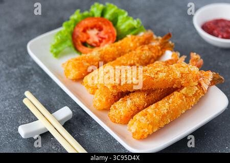 Golden crispy fried shrimp arranged on white textured plate. Lime ...