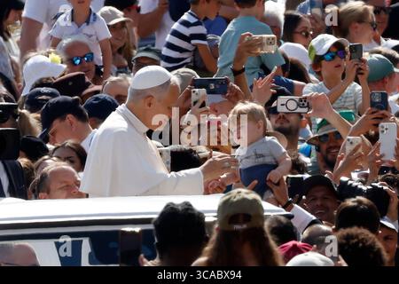 Pope Leo XIV greets a child as he arrives for his weekly general ...