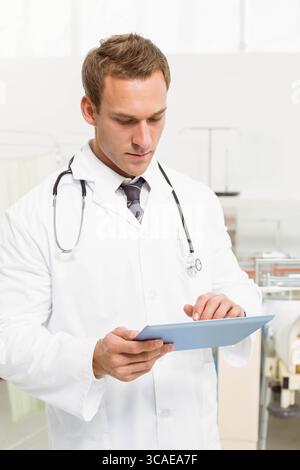 Doctor wearing stethoscope reviewing data on clipboard in clinic, with ...