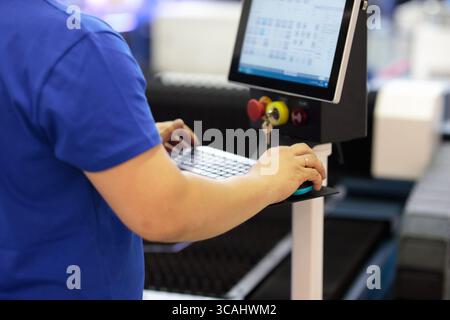 Operator of CNC machine working with control panel. Selective focus ...