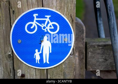blue and white multi use cycle and footpath sign on a grey wood fence ...