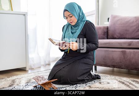 Young Muslim woman with Koran praying on yellow background Stock Photo ...
