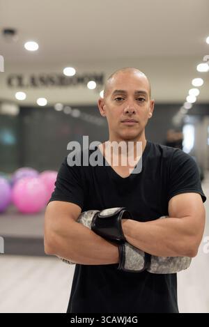 Hispanic bald man wearing boxing gloves posing as fighter or coach ...