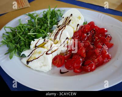 Green plate with traditional Italian Caprese salad and olive oil ...