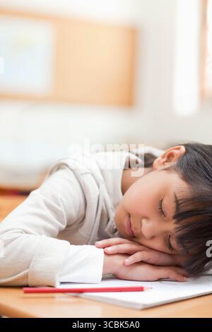 Close up of sleepy girl that leaning on table Stock Photo - Alamy