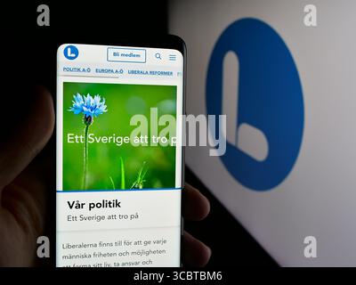 Person holding cellphone with logo of Swedish communications company ...