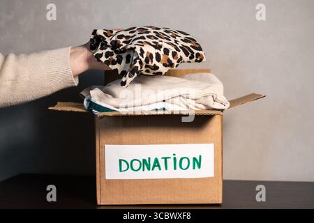 Cardboard box full of clothing ready for donation. Modern eco friendly ...