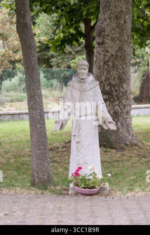Grado, Italy - June 24, 2025: Stone statue of a friar with open arms ...
