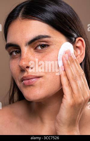 Makeup removal. A beautiful young woman wiping the make-up off her face ...