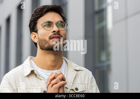 Indian businessman clasping hands wishing luck praying with closed eyes ...