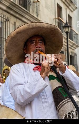 A musician with vitiligo playing a wooden flute in a parade during the ...