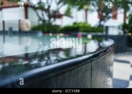 Infinity edge pool surface with clear water flowing over black tile in ...