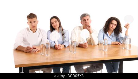 Panel of judges with blank score signs at table on white background ...