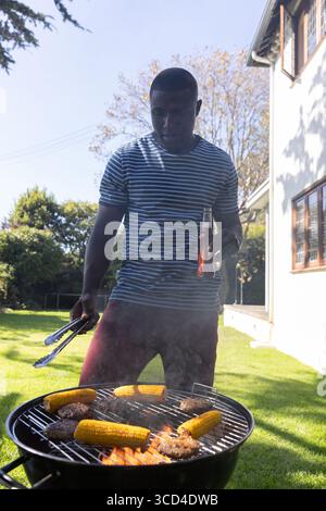 Man grilling burgers on a barbecue in a luxury glamping resort ...