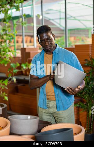 African american man chooses flower pots for indoor plants Stock Photo ...