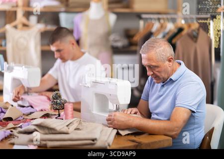 Two male workers in the atelier sewing Stock Photo - Alamy