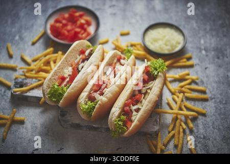 Assortment of three tasety hot dogs, placed on wooden cutting board ...