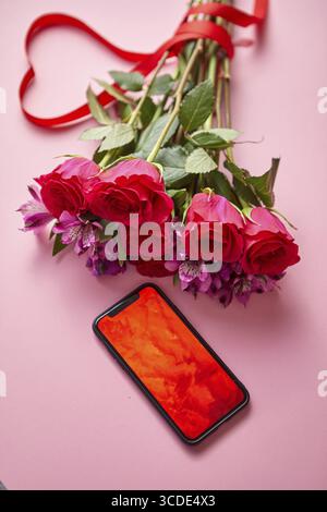 Pink roses bouquet with hart shaped bow and mobile phone with copy ...