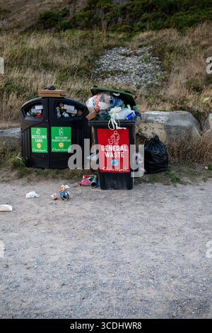 Overflow flowing rubbish bins next to the beach in southern England ...