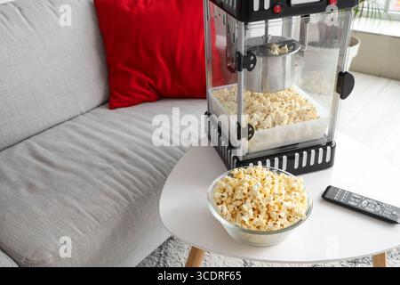 Modern popcorn machine and TV remote on coffee table in living room ...