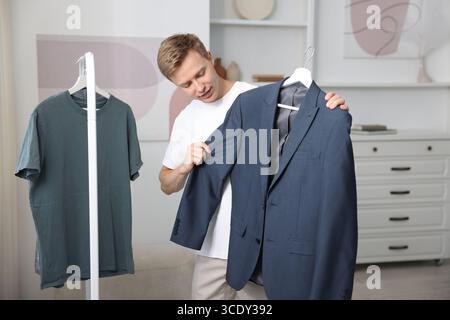 Getting ready. Young man choosing clothes at home Stock Photo - Alamy