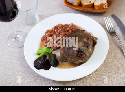 Baked pork cheek with stewed pinto beans and greens Stock Photo - Alamy