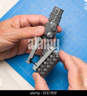 Man fitting polystyrene scale model parts together to check fit before ...