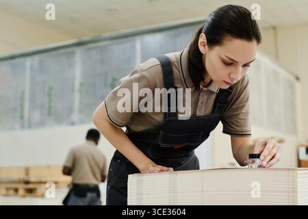 Woman using a magnifying glass to check the authenticity of a leather ...