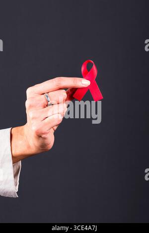 AIDS and HIV awareness concept. Red satin ribbon bow and stethoscope on ...