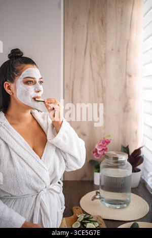 Young woman drinking cucumber water on blue background Stock Photo - Alamy