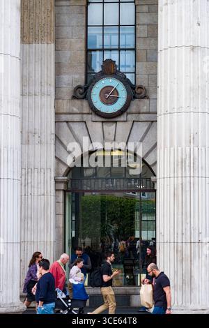 People walking past the Ionic portico with fluted Ionic columns of the ...