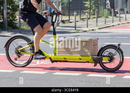Man in shorts rides cargo bike Stock Photo - Alamy