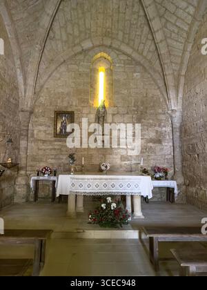 Simple Romanesque altar with flowers, statue and stone vault inside ...