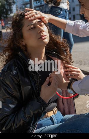 Woman doctor touching forehead of sick man on the street Stock Photo ...